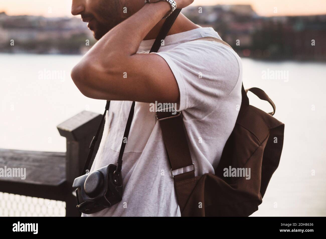 Male tourist wearing camera strap around neck while standing by river ...