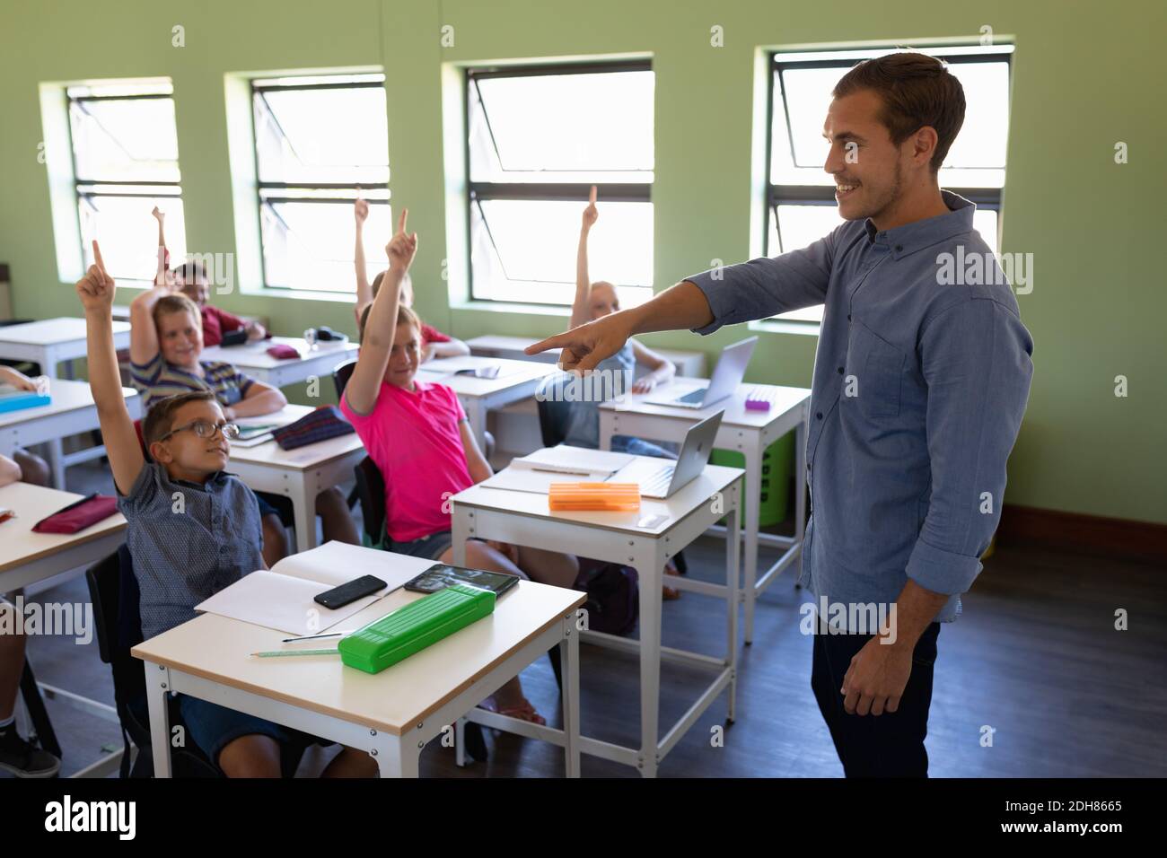 Male school teacher standing in an elementary school classroom with a ...