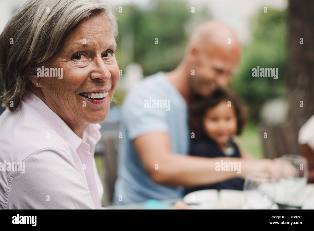 Side view portrait of happy senior woman with family having food at ...
