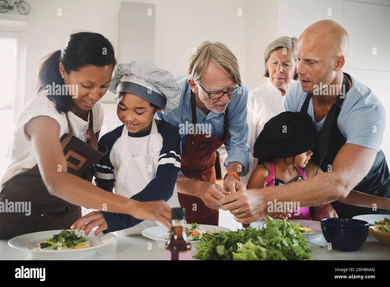 Multi-generational family preparing food at table in kitchen Stock ...