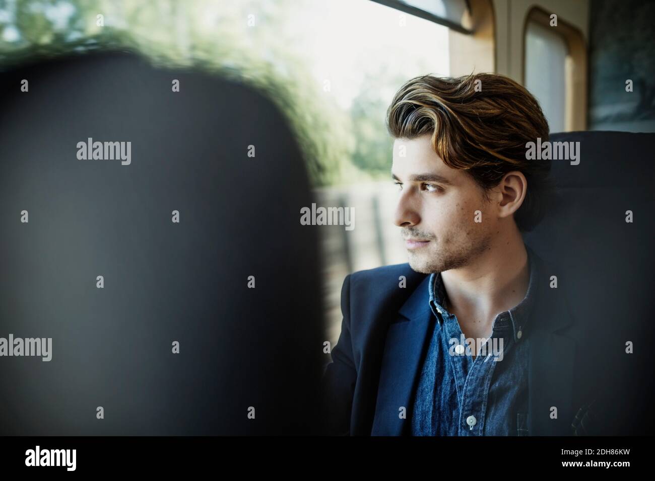Thoughtful businessman looking through train window Stock Photo - Alamy