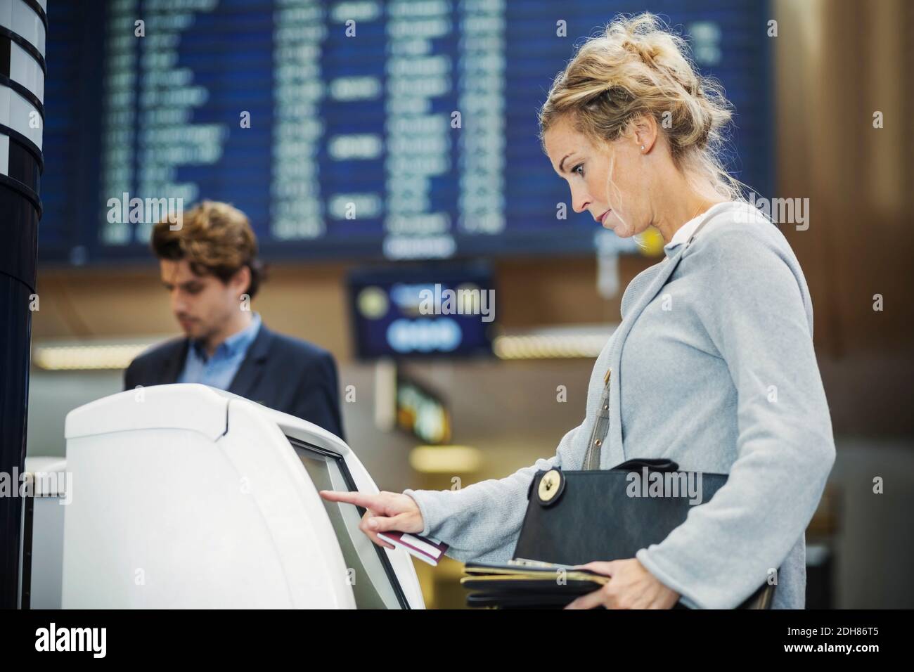 Side view of businesswoman using check in machine at airport Stock ...