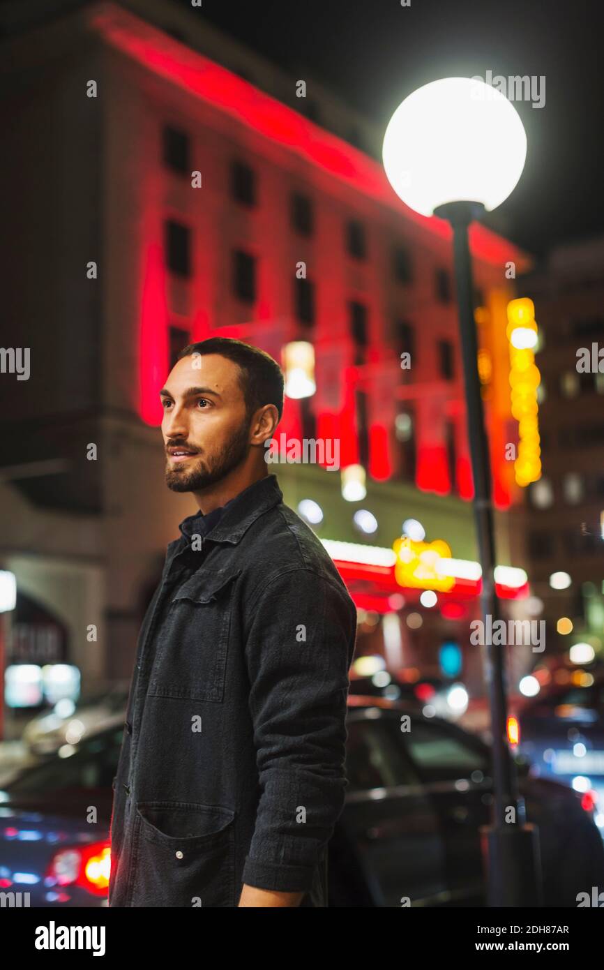 Side view of man looking away while standing in city at night Stock ...