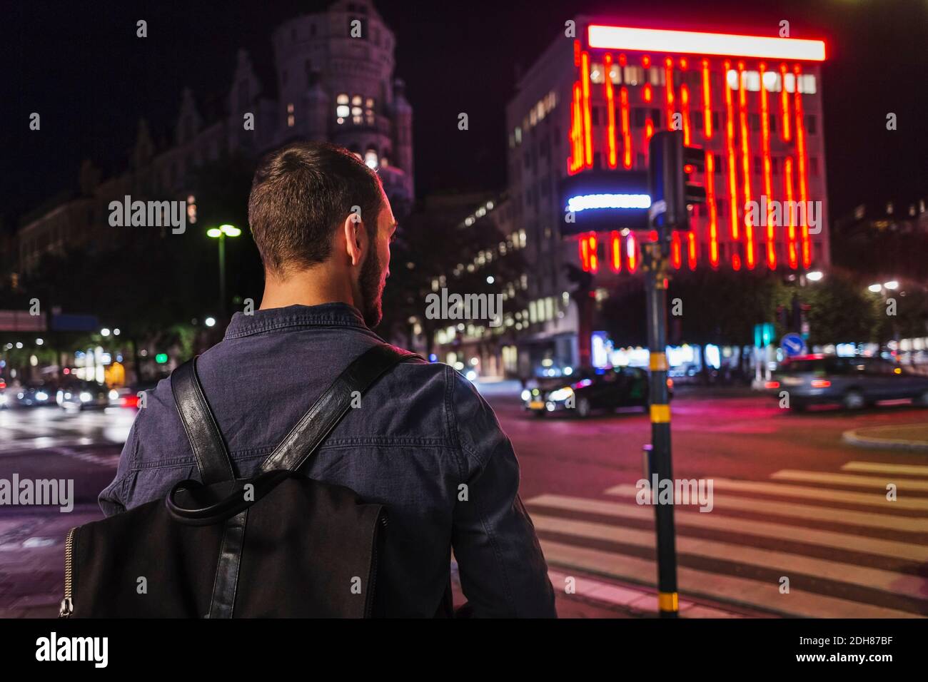 Rear view of man carrying backpack while standing on city street at ...