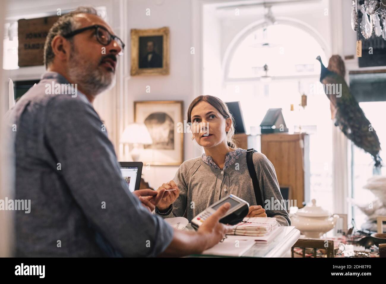 Owner with female customer at shop counter Stock Photo - Alamy