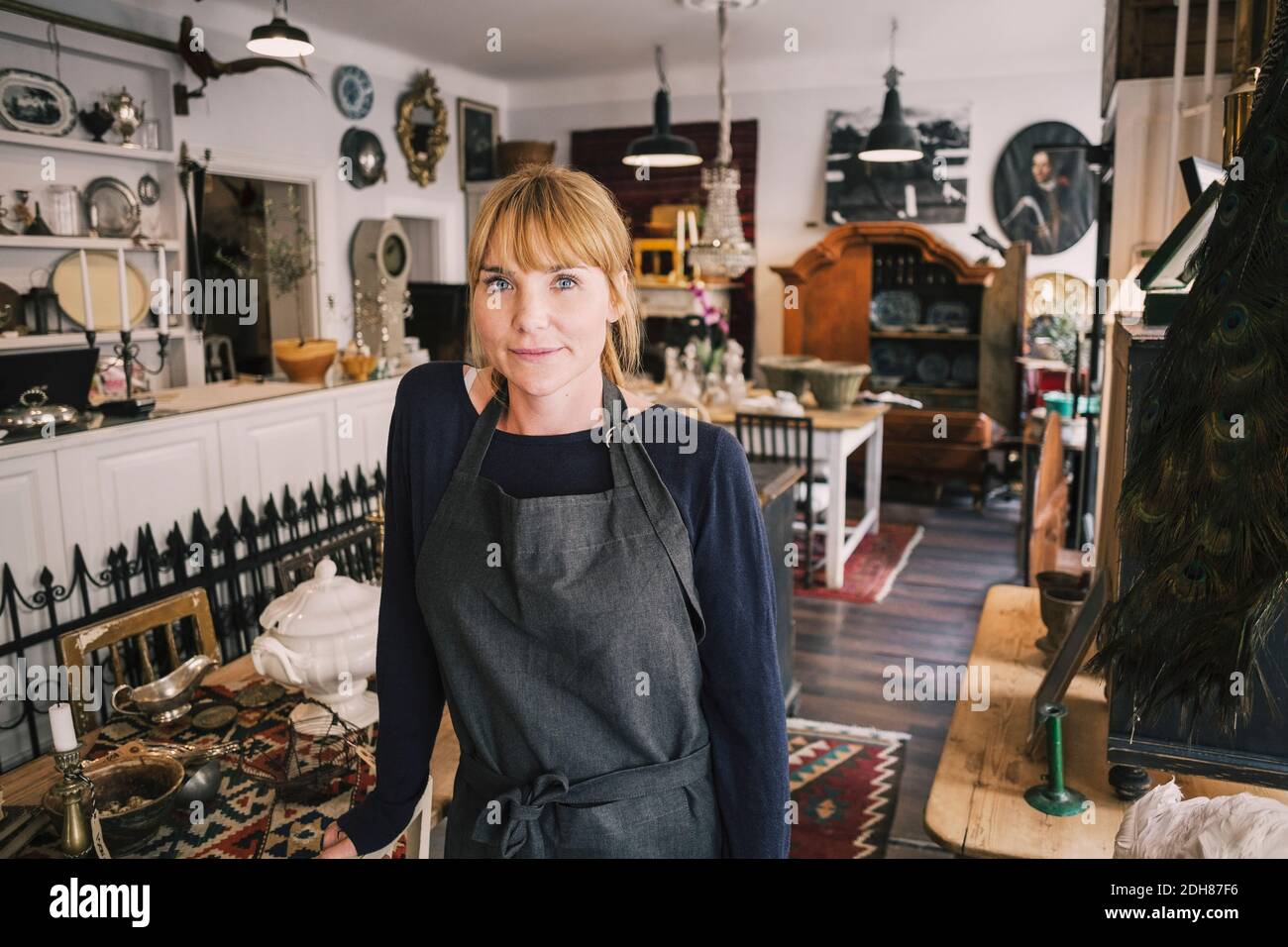 Portrait of confident owner standing by table in antique store Stock ...