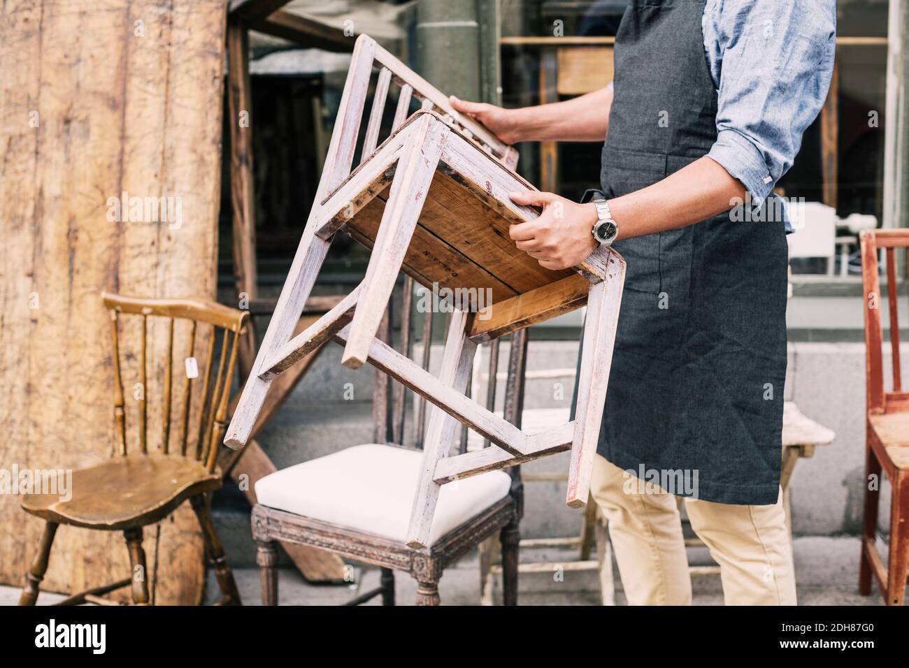 Midsection of man holding chair while standing against store Stock ...