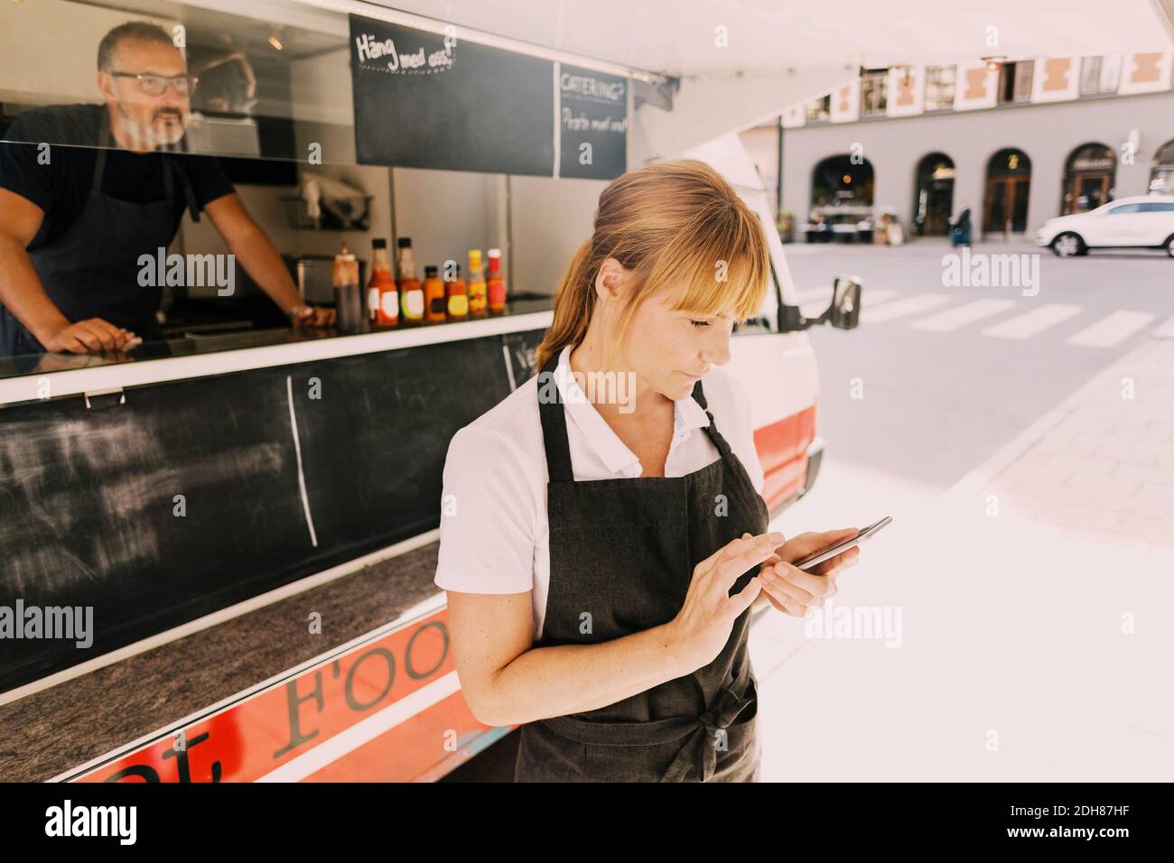 Female chef using mobile phone by food truck at city street Stock Photo ...