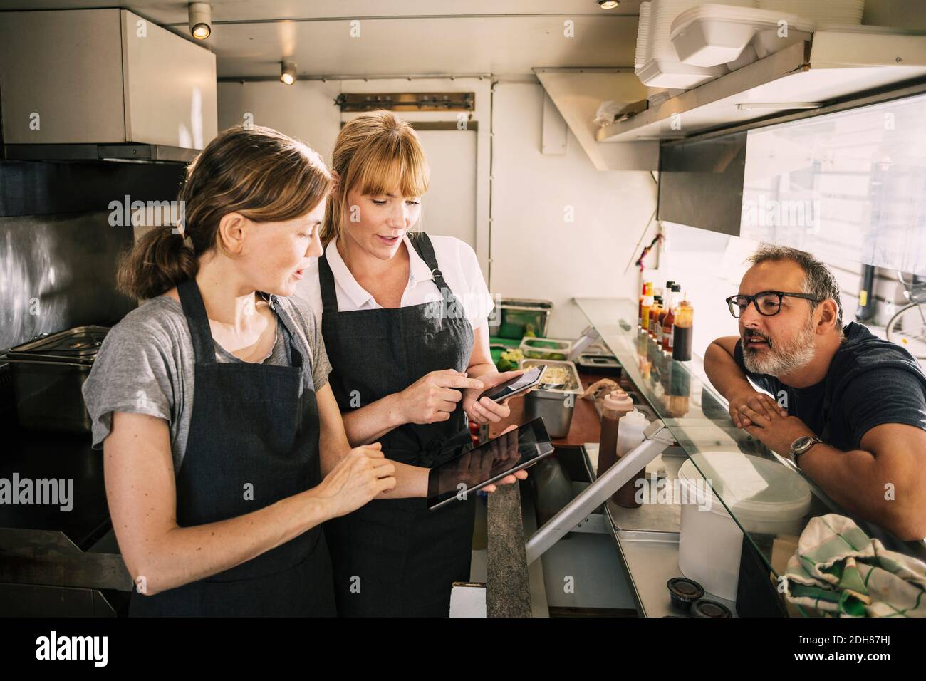 Female chefs with technologies while receiving order from man in food ...