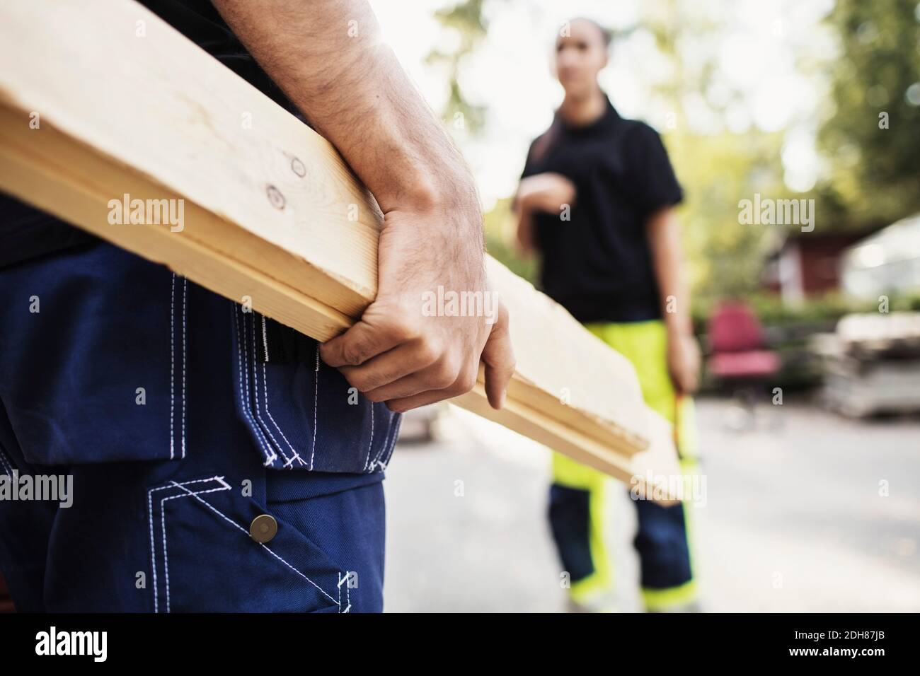 Midsection of male student carrying wooden planks with classmate ...