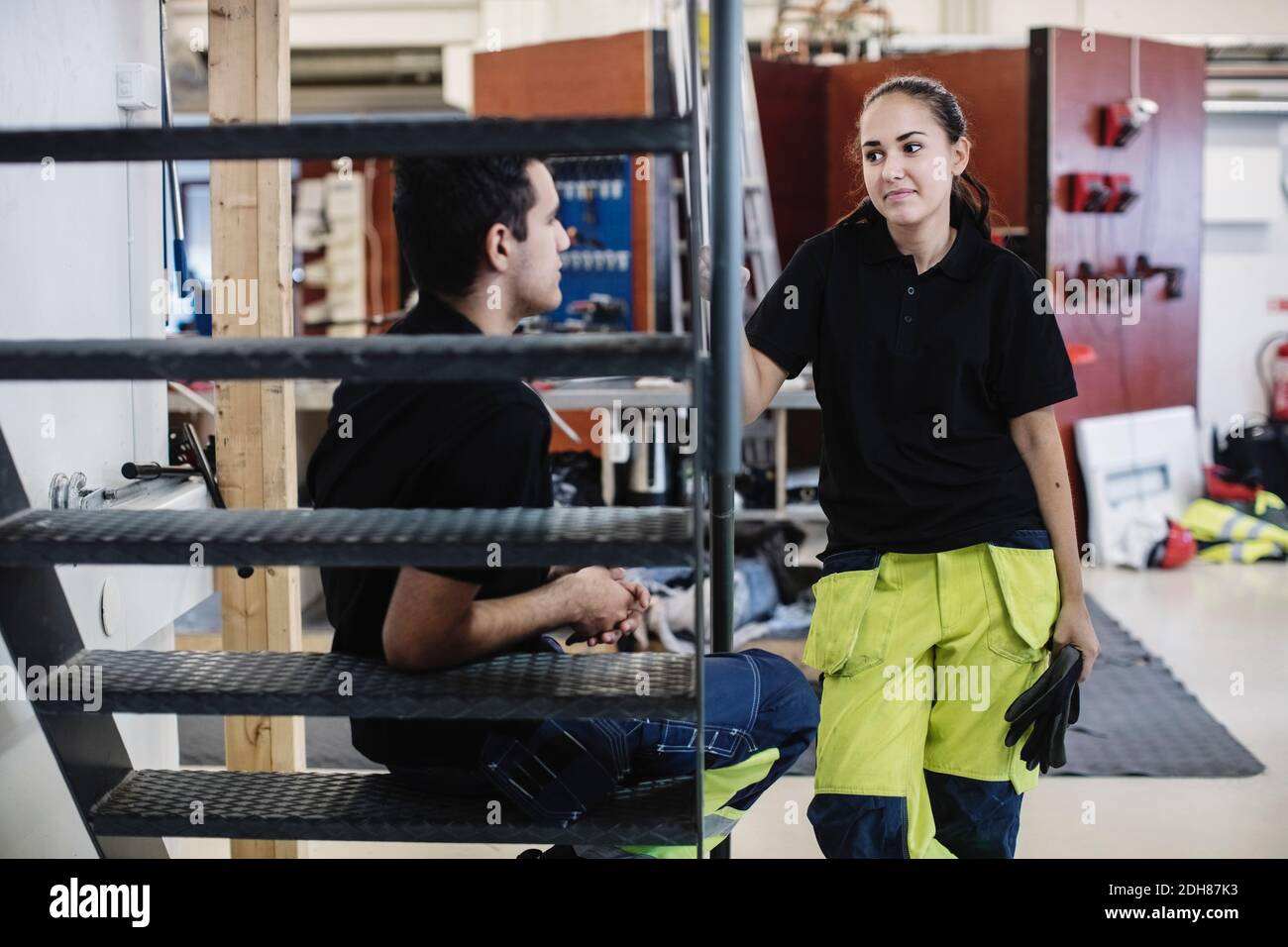Female auto mechanic student looking at male friend at workshop Stock ...