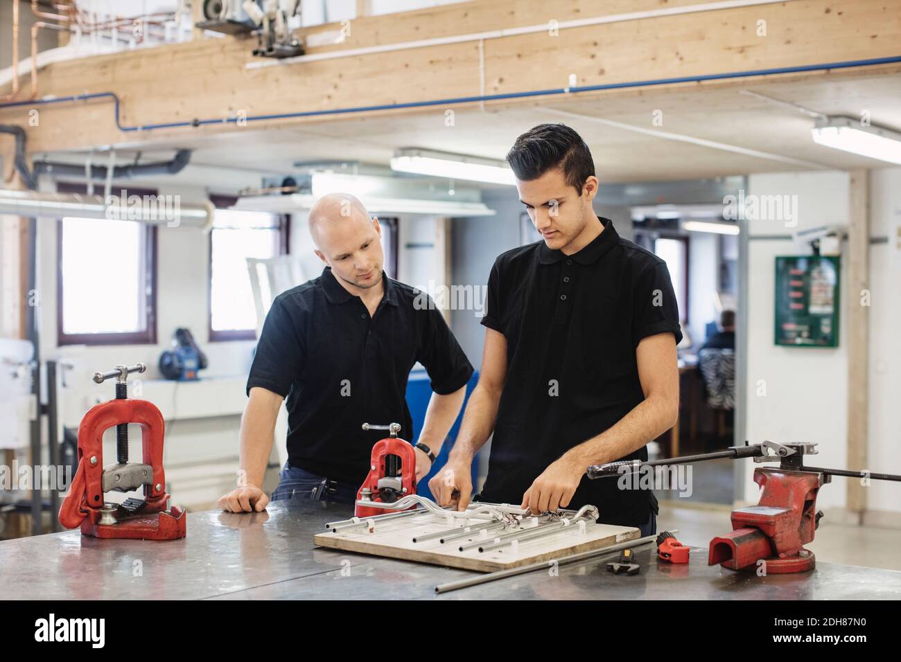 Auto mechanic teacher looking at male student working at workshop Stock ...