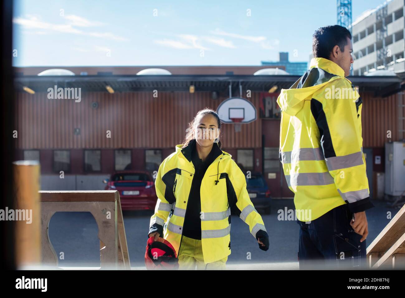 Smiling female auto mechanic student with male friend seen through ...