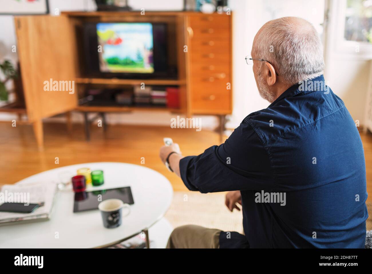 Rear view of senior man changing channels at home Stock Photo - Alamy