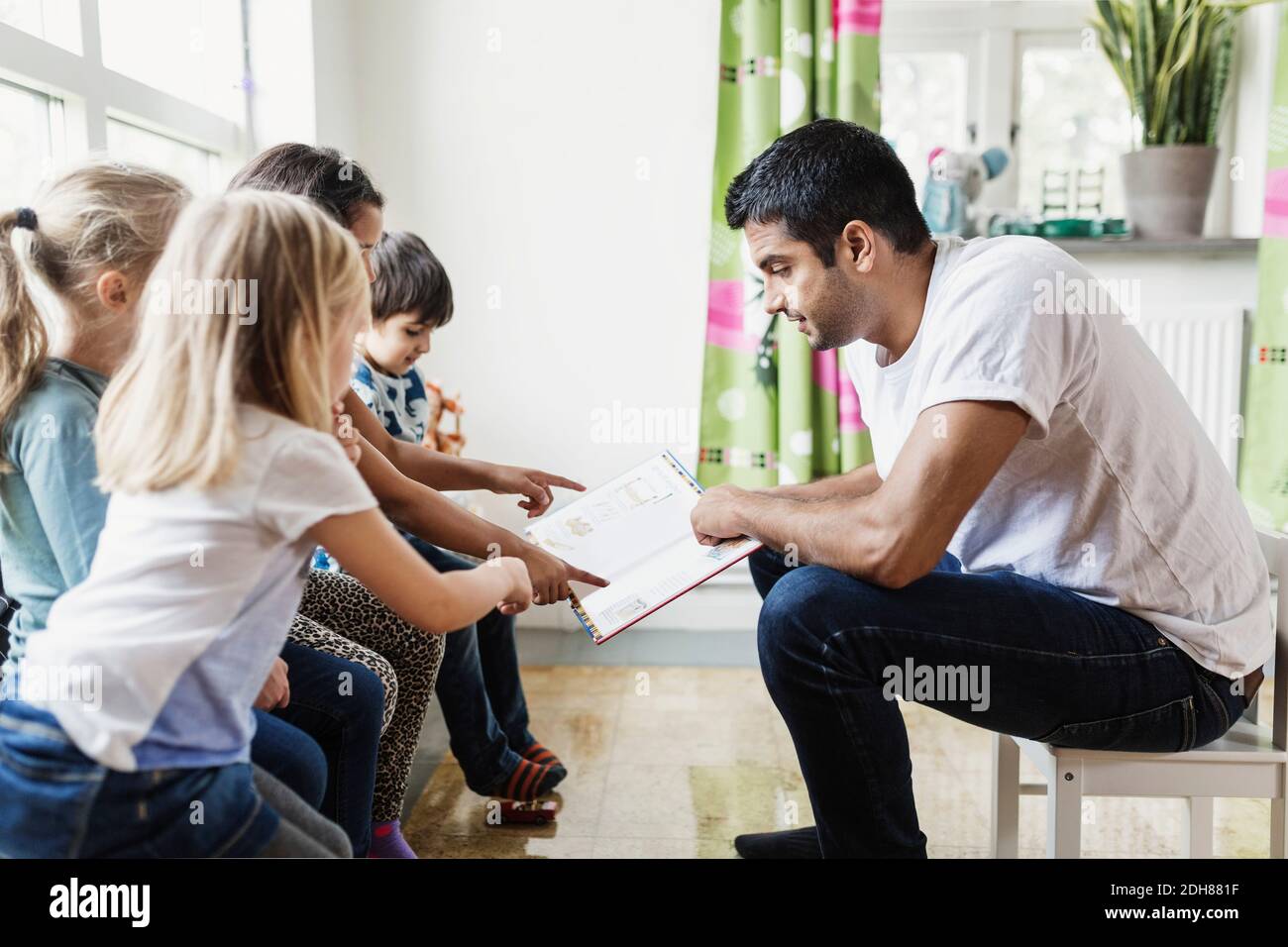 Side view of teacher and students reading book in classroom Stock Photo ...