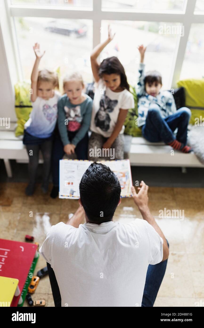 High angle view of male teacher asking questions to students at day ...