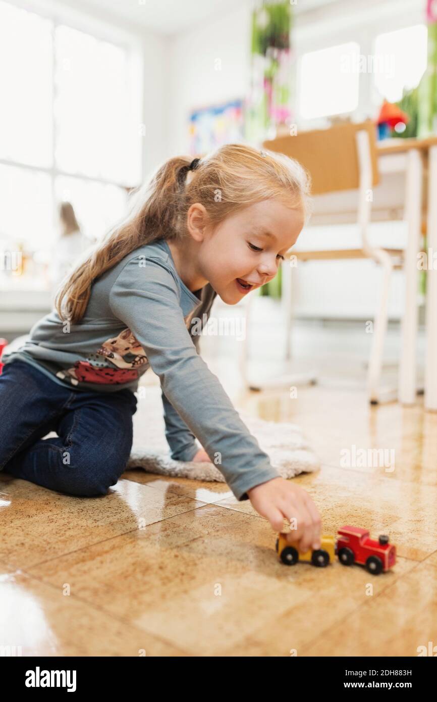 Happy girl playing with toy car on floor at classroom Stock Photo - Alamy