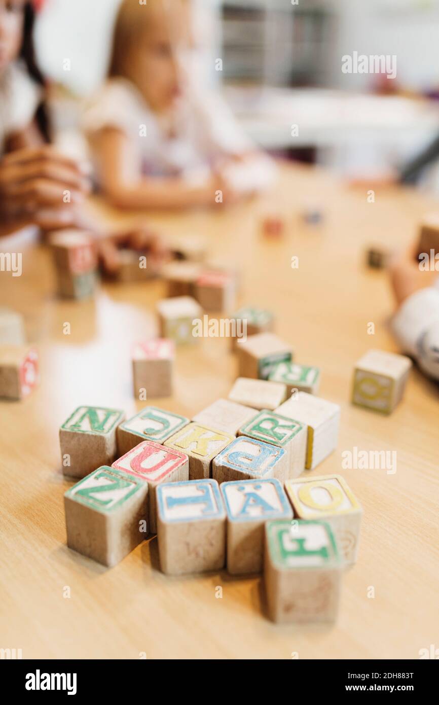 Alphabet blocks on table with children sitting in background Stock ...