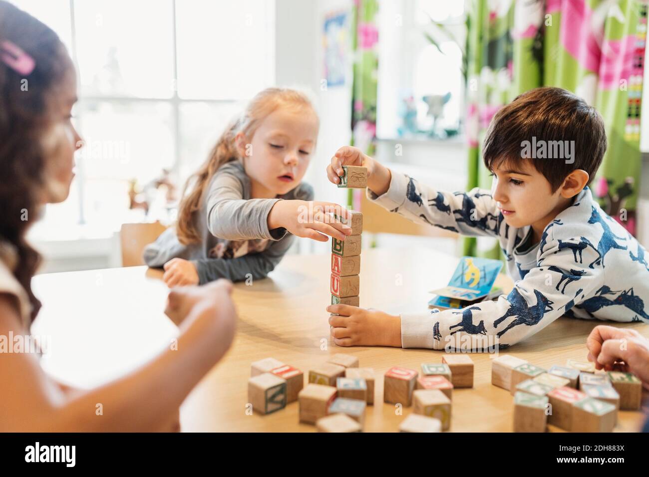 Children stacking alphabet blocks on table Stock Photo - Alamy