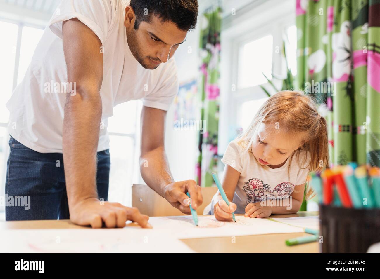 Male children assisting little girl in drawing at classroom Stock Photo ...