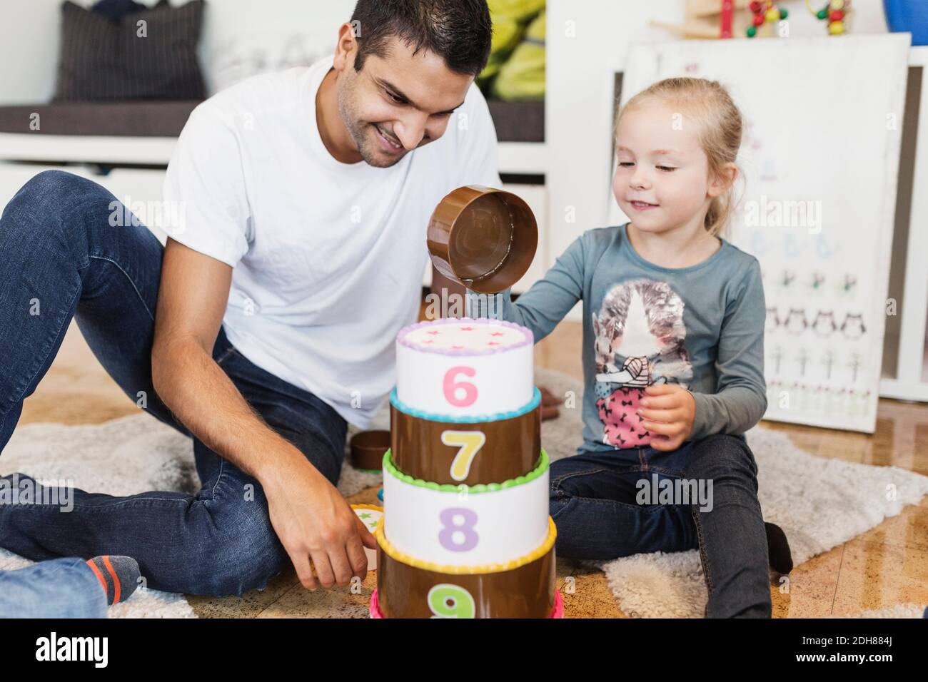 Happy girl stacking number blocks by teacher in classroom Stock Photo ...