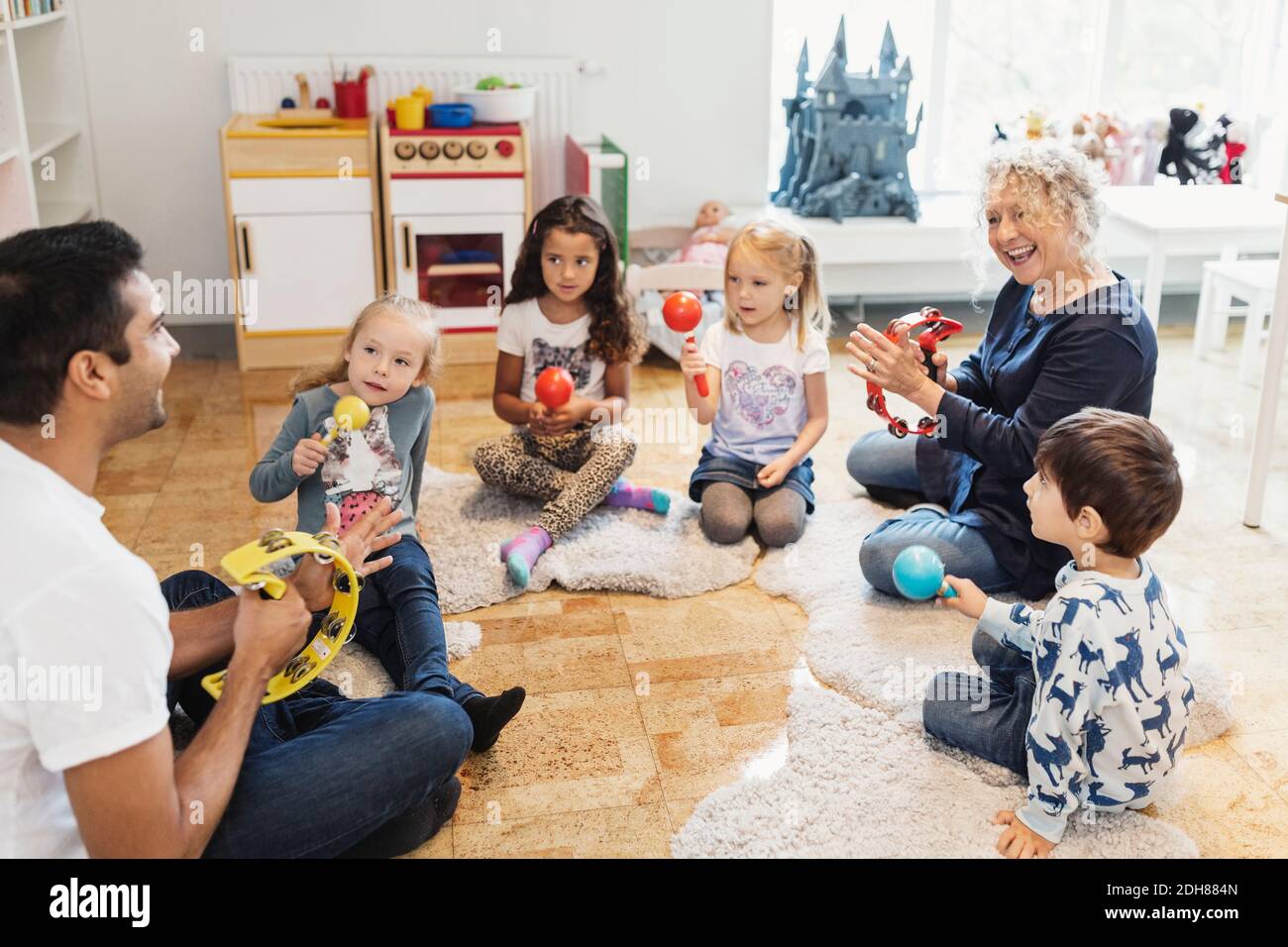 Happy teachers and children holding musical instruments in classroom ...