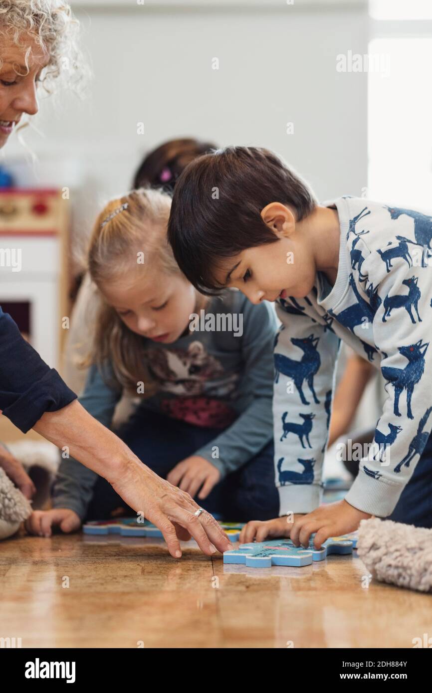 Teacher and children playing jigsaw puzzle Stock Photo - Alamy