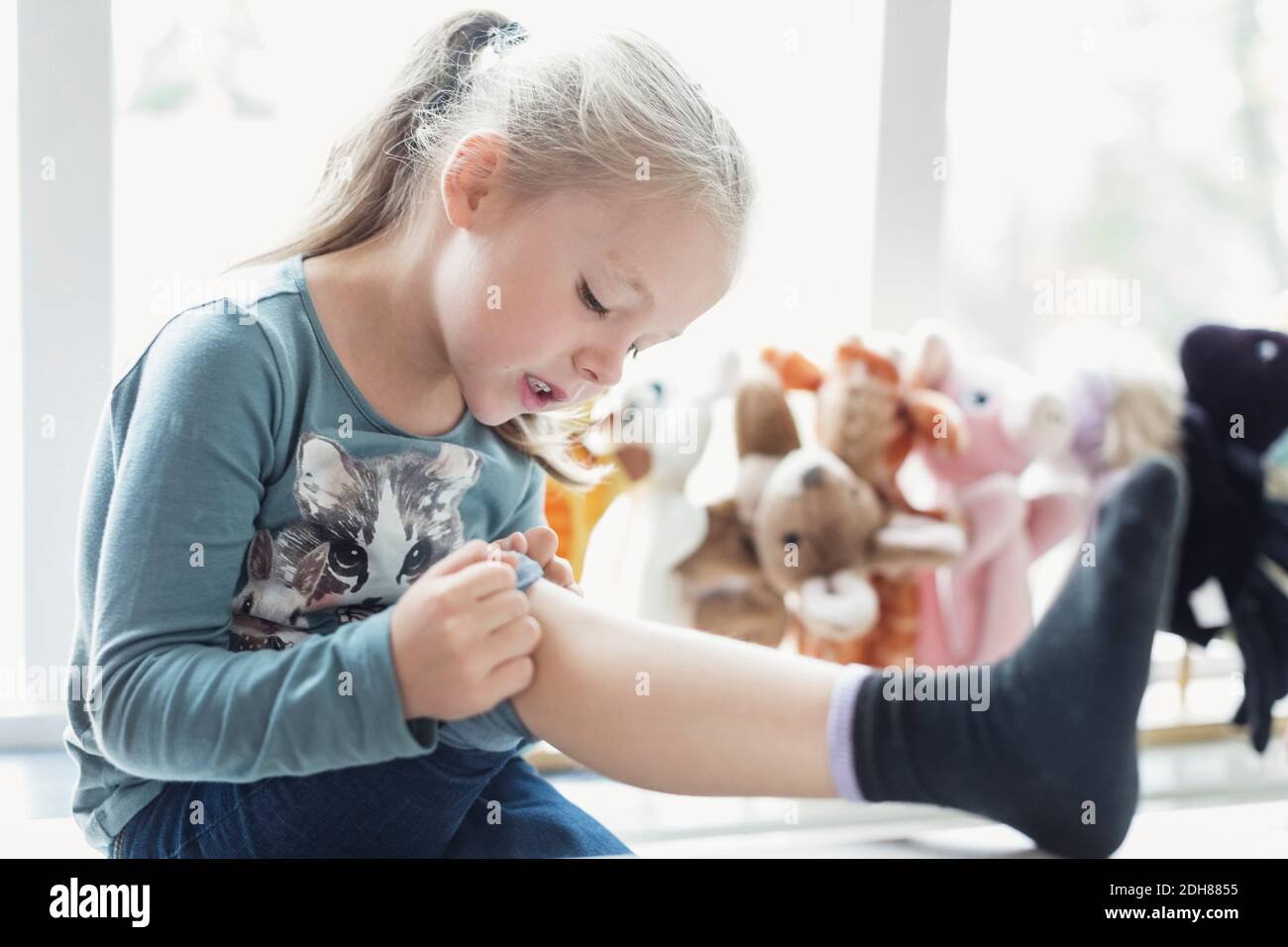 Little girl looking at injured knee in classroom Stock Photo - Alamy
