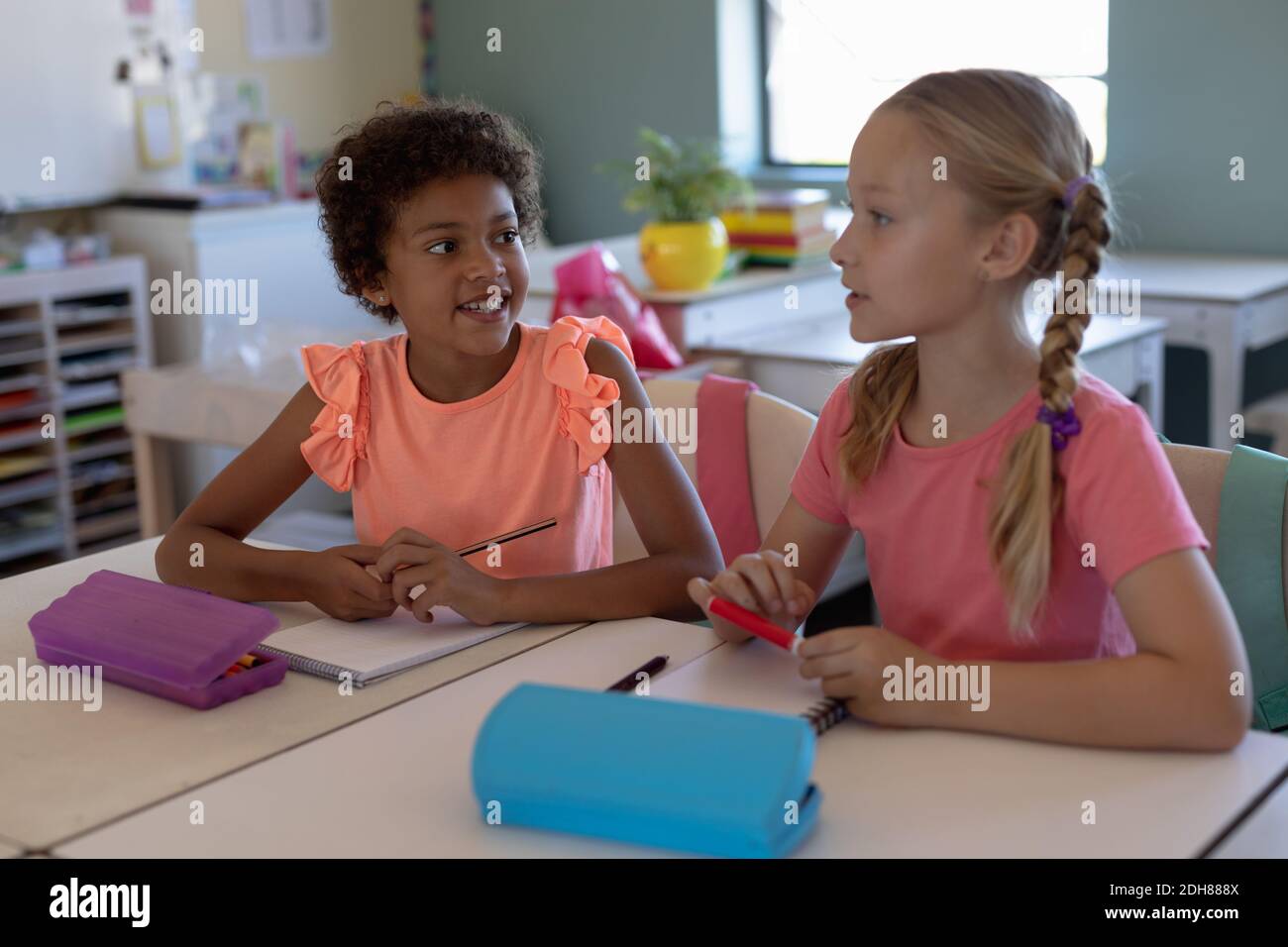 Schoolgirls talking during a lesson in an elementary school classroom ...