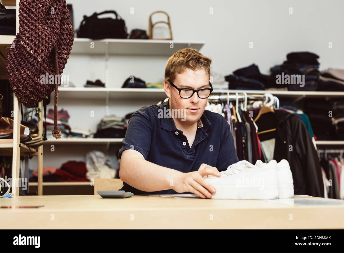 Cashier holding shoes on table while calculating in clothing store ...