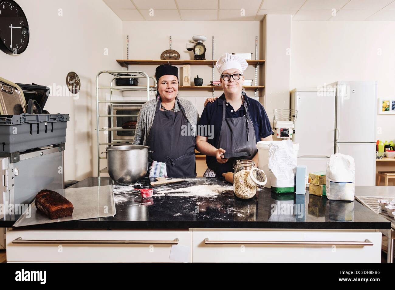 Portrait of bakers standing by kitchen counter Stock Photo - Alamy