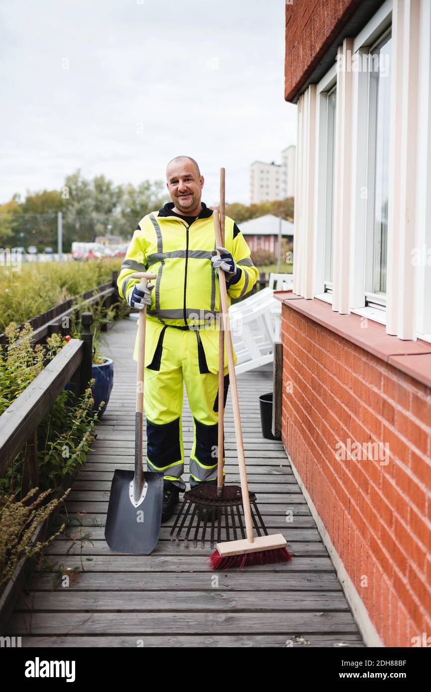 Portrait of smiling man holding broom and equipment Stock Photo - Alamy