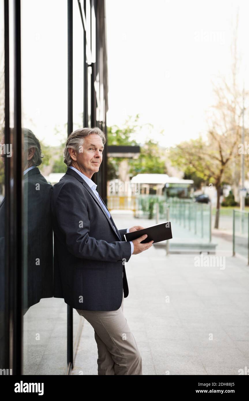 Side view senior man standing outdoors with book Stock Photo - Alamy