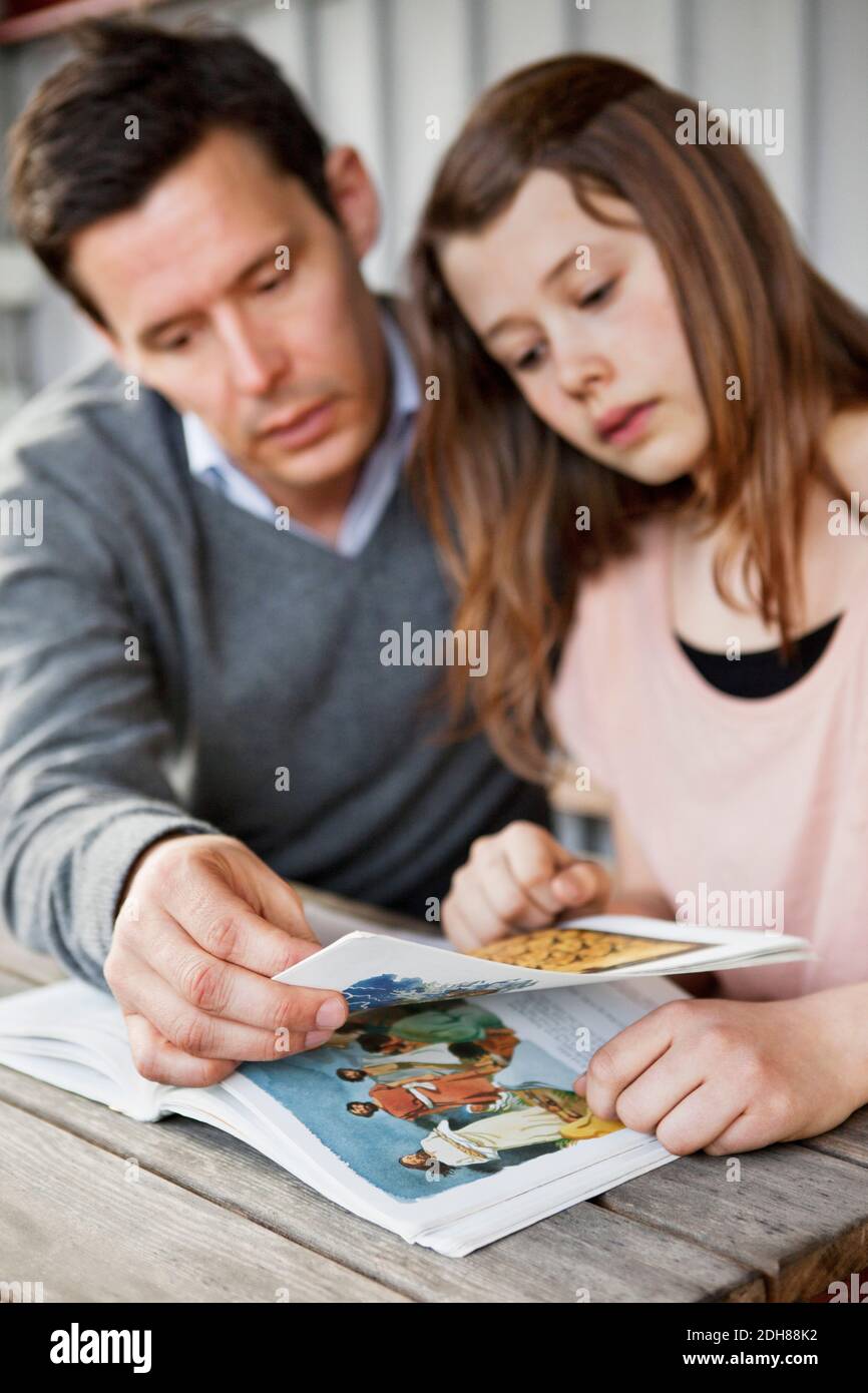 Father helping daughter understand while reading book Stock Photo - Alamy