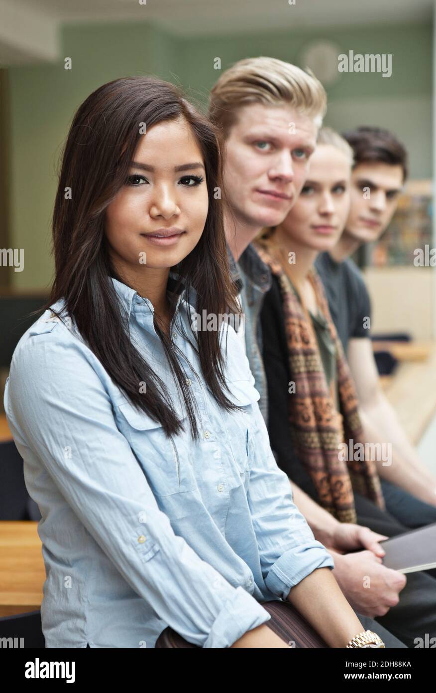 Portrait of confident friends sitting side by side Stock Photo - Alamy