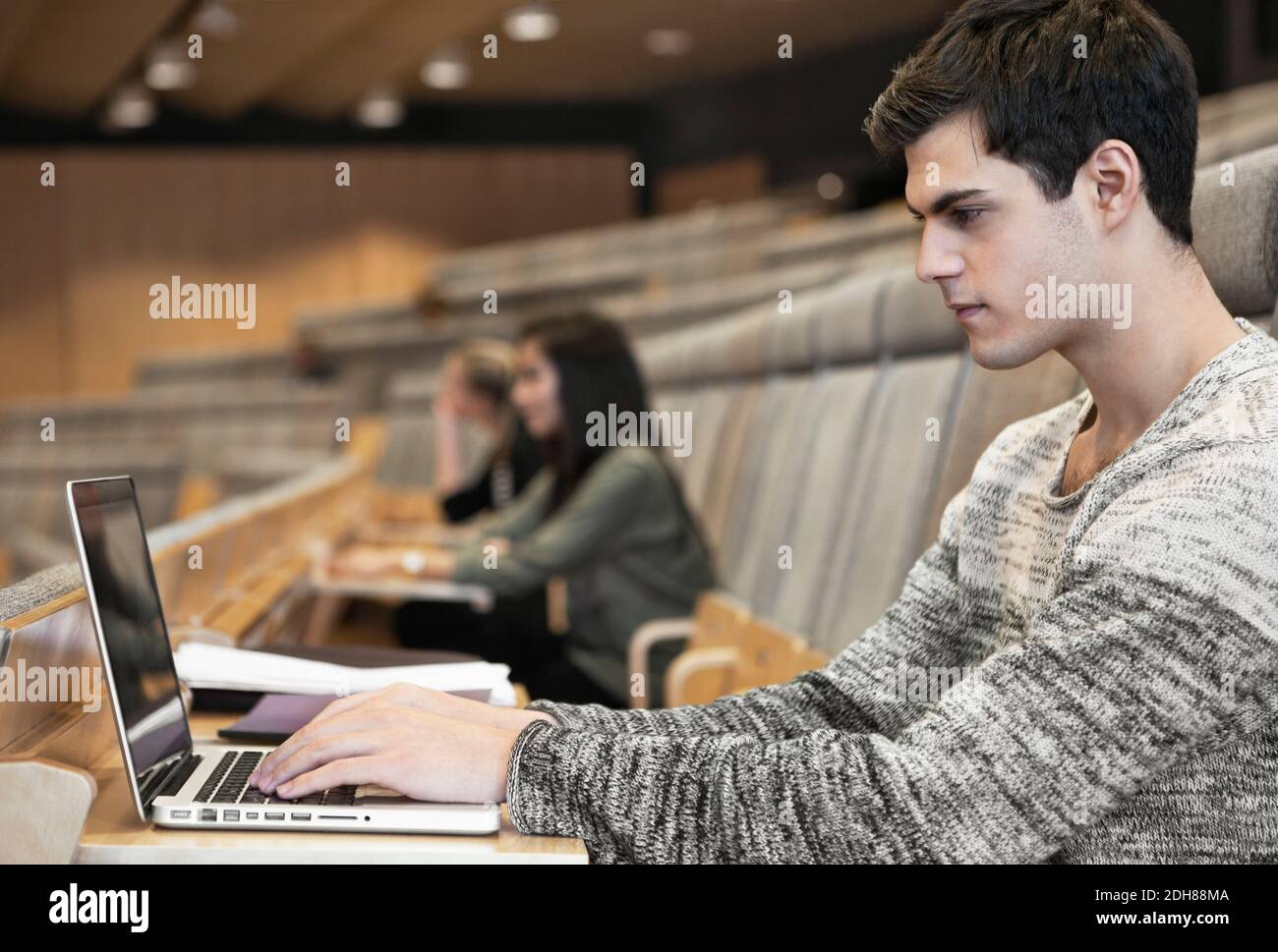 Side view of handsome young man using laptop in convention center Stock ...