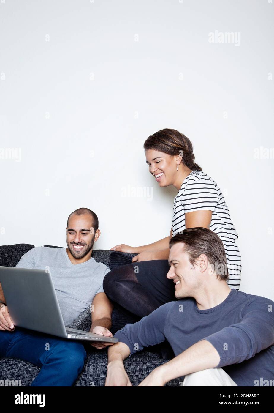 Three mid adult friends using laptop together Stock Photo - Alamy