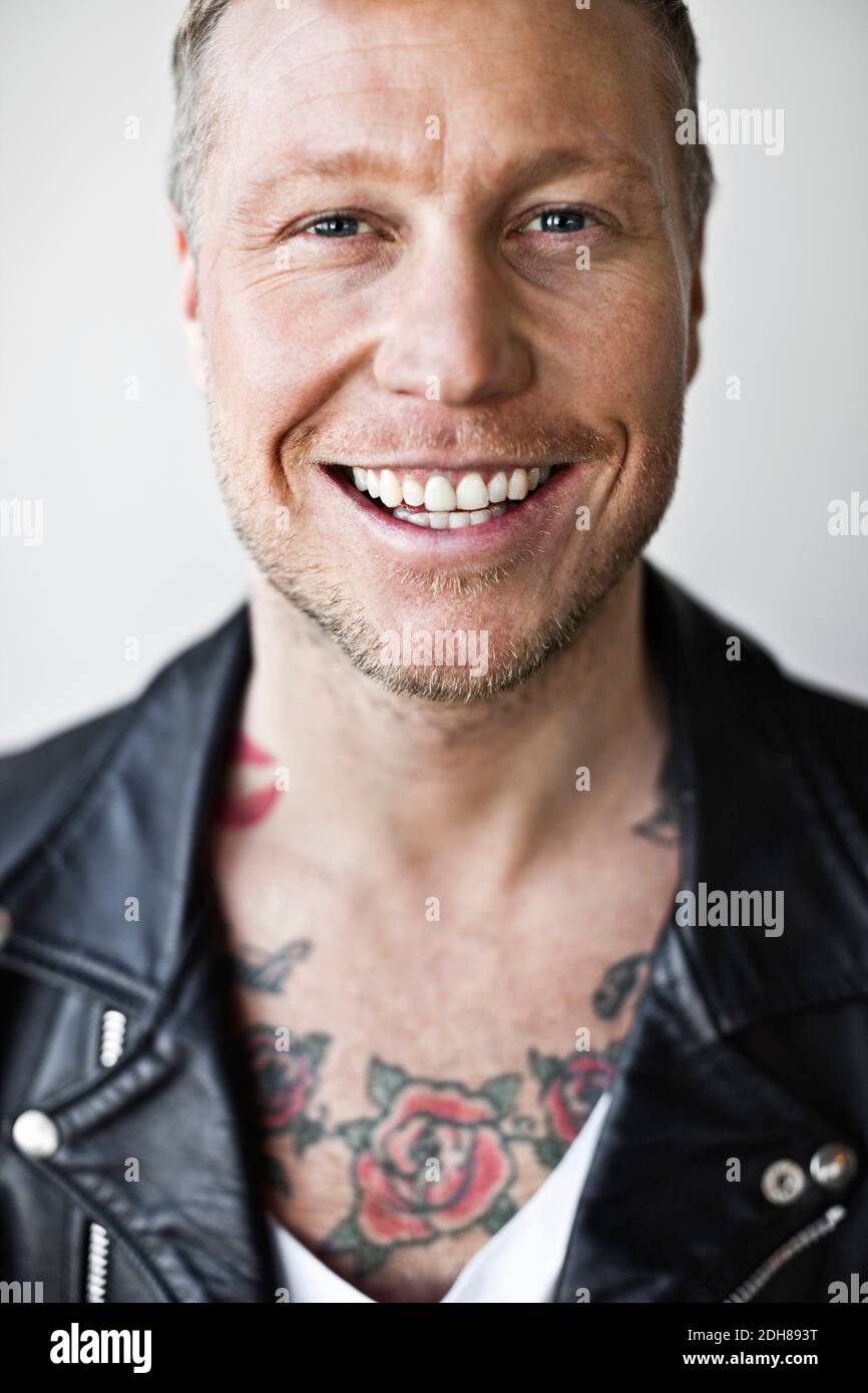Close-up portrait of a happy mid adult man smiling over grey background ...