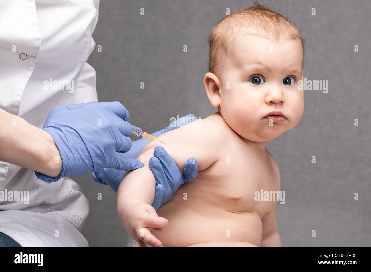 Pediatrician or nurse giving an intramuscular injection of a vaccine to ...