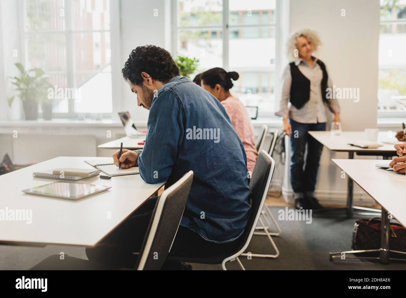Teacher explaining while students writing in language class Stock Photo ...