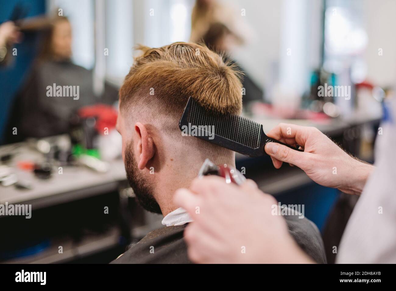 Close up shot of man getting trendy haircut at barber shop. Male ...