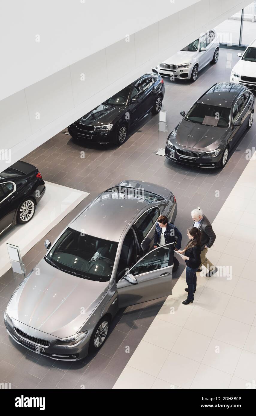 High angle view of saleswoman explaining to customers at car showroom ...