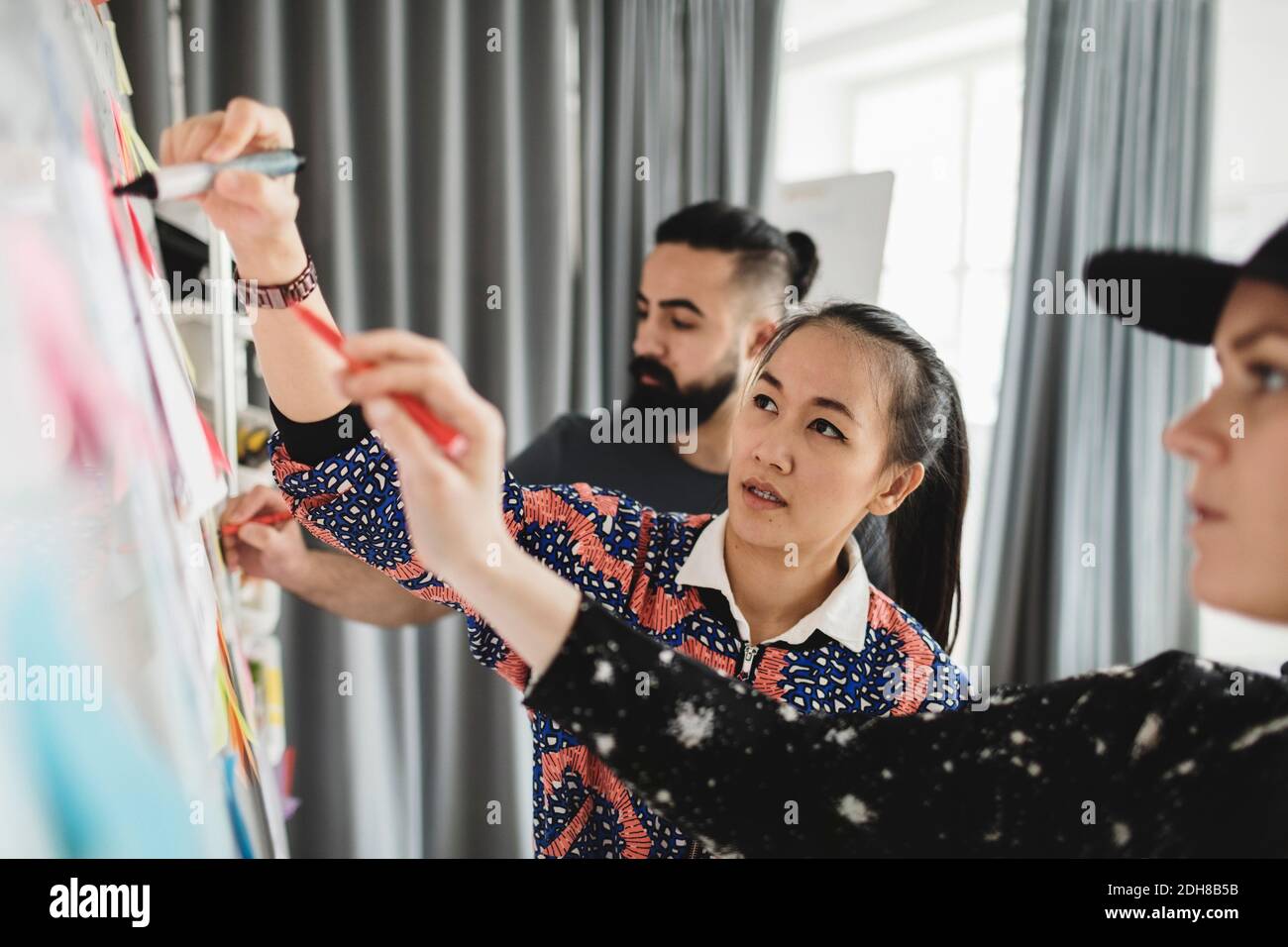 Business people writing on whiteboard in board room at creative office ...