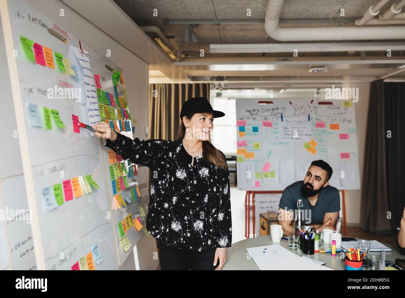 Businesswoman showing whiteboard and explaining colleagues in board ...