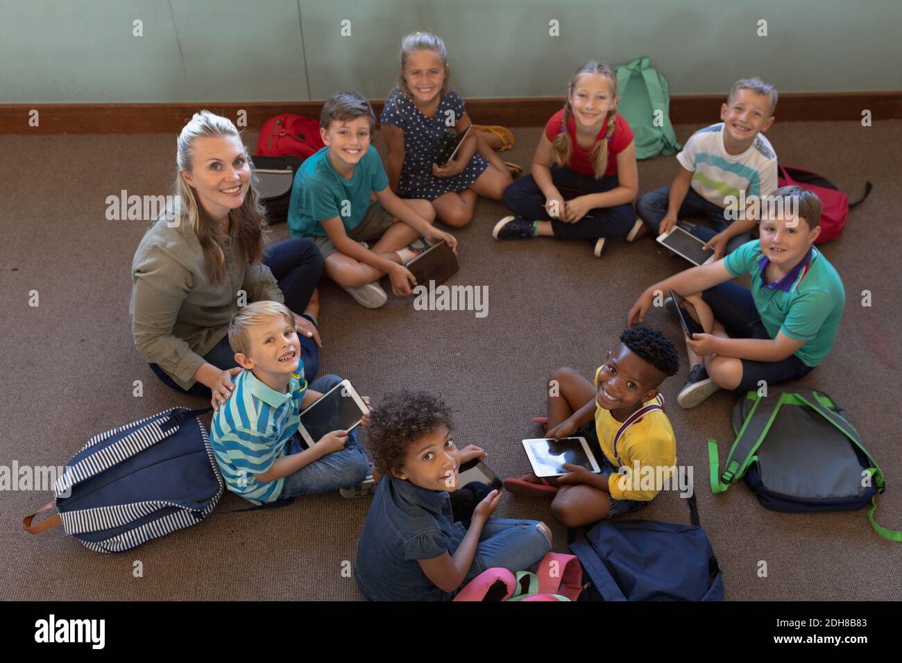 Female school teacher sitting cross legged on the floor in a circle ...