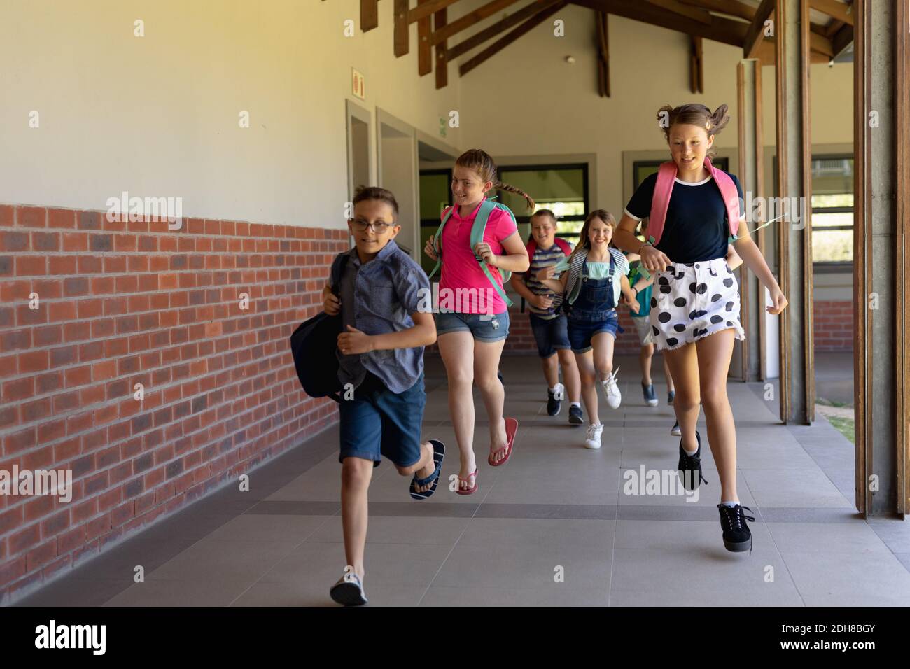 Group of schoolchildren running in an outdoor corridor at elementary ...
