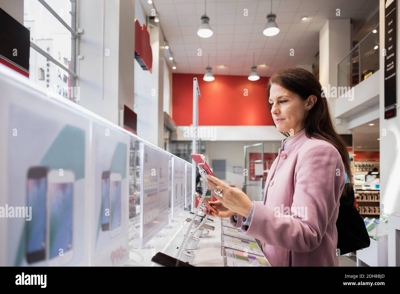 Side view of woman using smart phone in store Stock Photo - Alamy