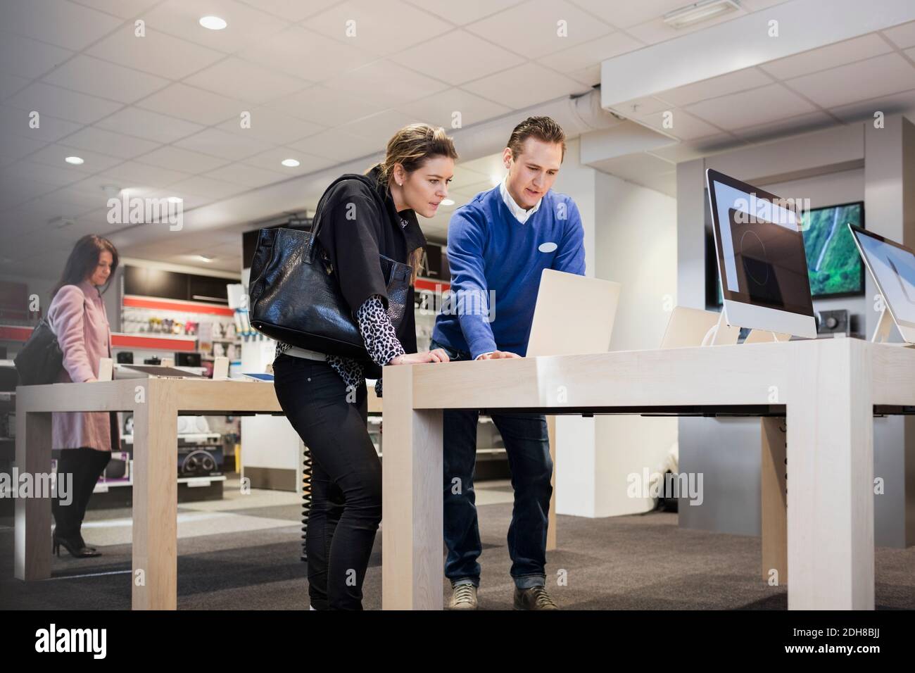 Salesman assisting female customer in buying laptop at store Stock ...