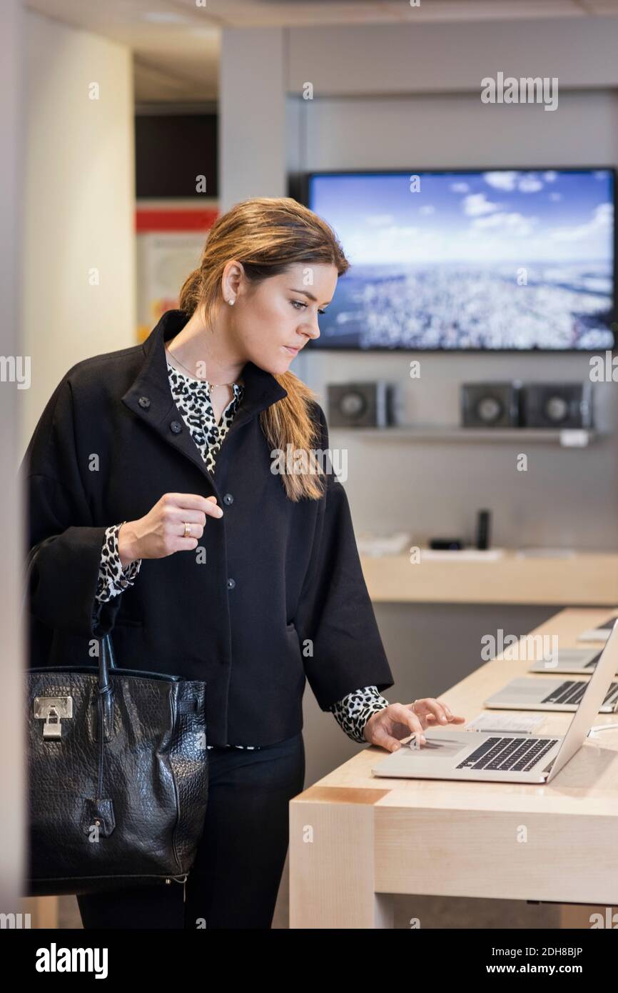 Female customer using laptop while standing at table in store Stock ...