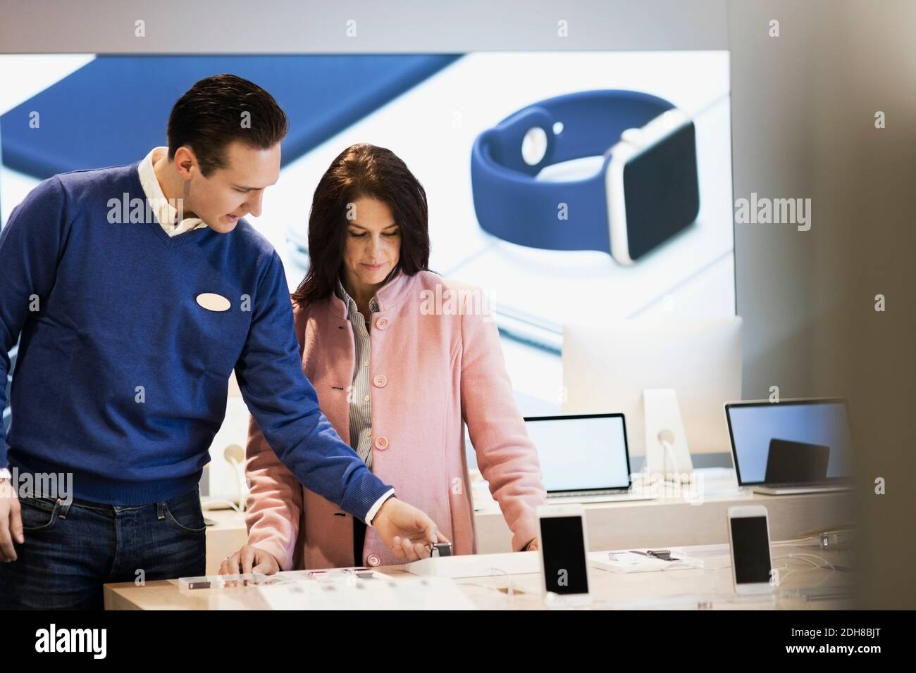 Salesman assisting customer in buying smart watch at store Stock Photo ...